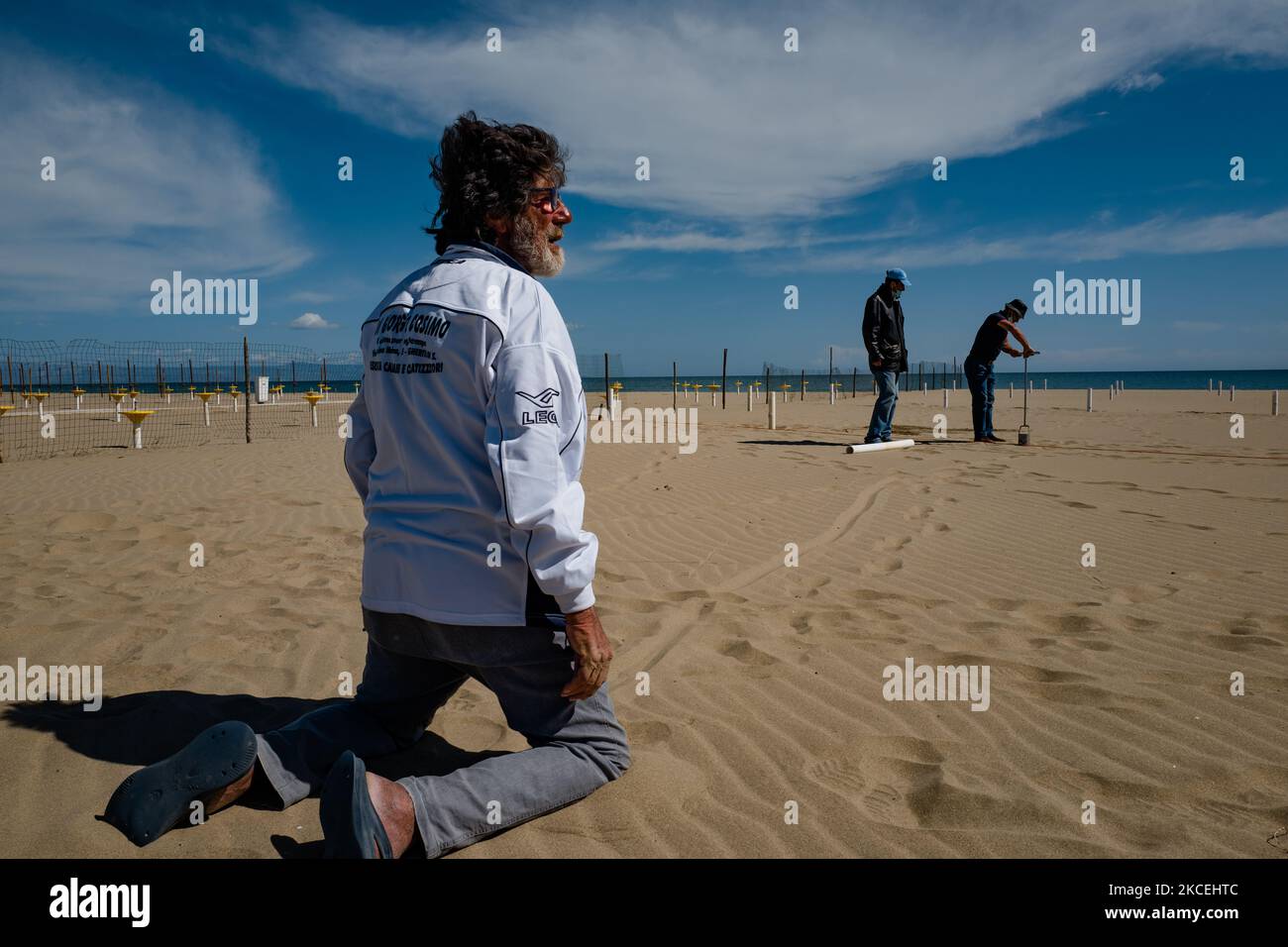 The owner of a bathing beach with the workers place the poles for the ...