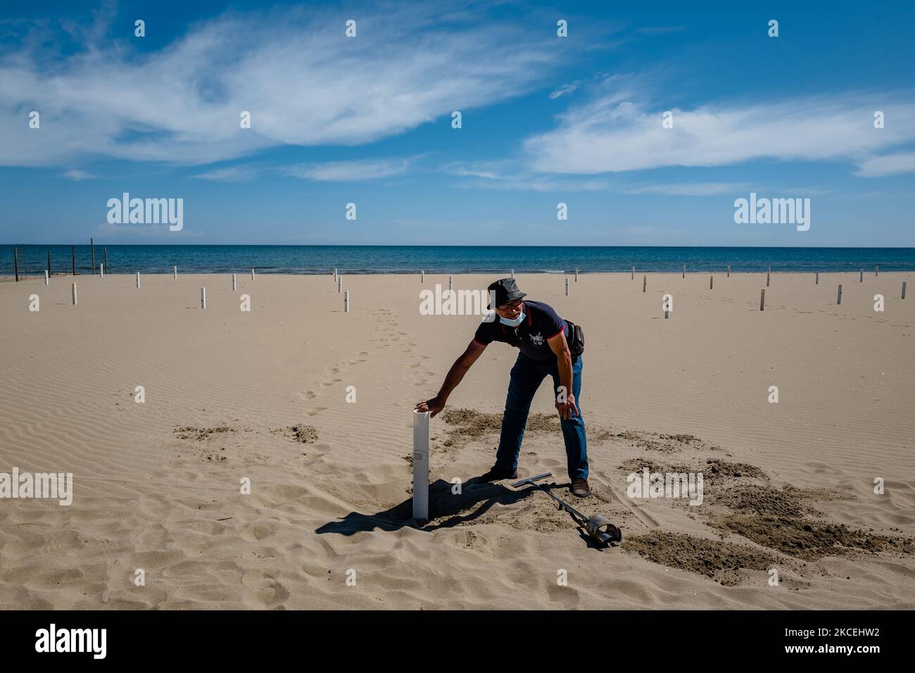 A worker places the poles for the umbrellas on the beach of Margherita ...