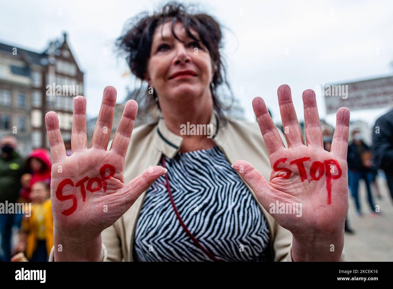 A woman is showing her hands with the word stop drawn on them, during ...