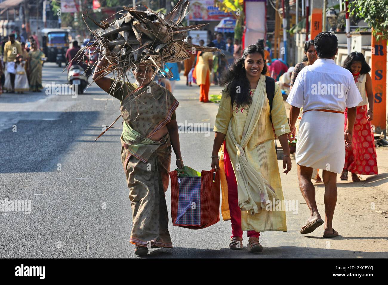 Hindu woman carries a bundle of dried coconut flower sheaths (kothumbu ...