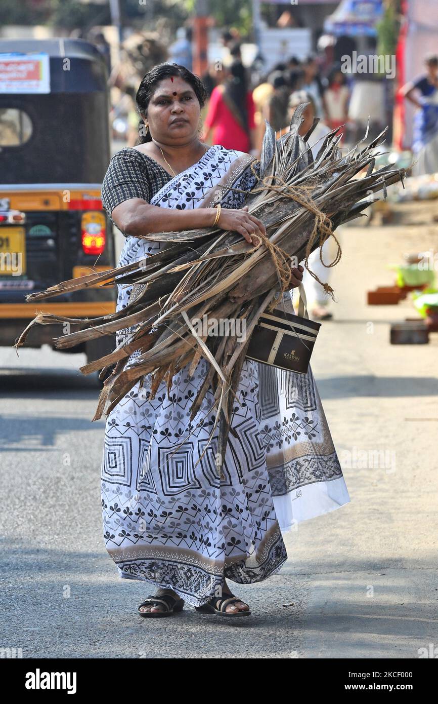 Hindu woman carries a bundle of dried coconut flower sheaths (kothumbu ...