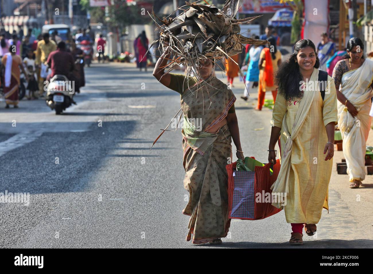 Hindu woman carries a bundle of dried coconut flower sheaths (kothumbu ...