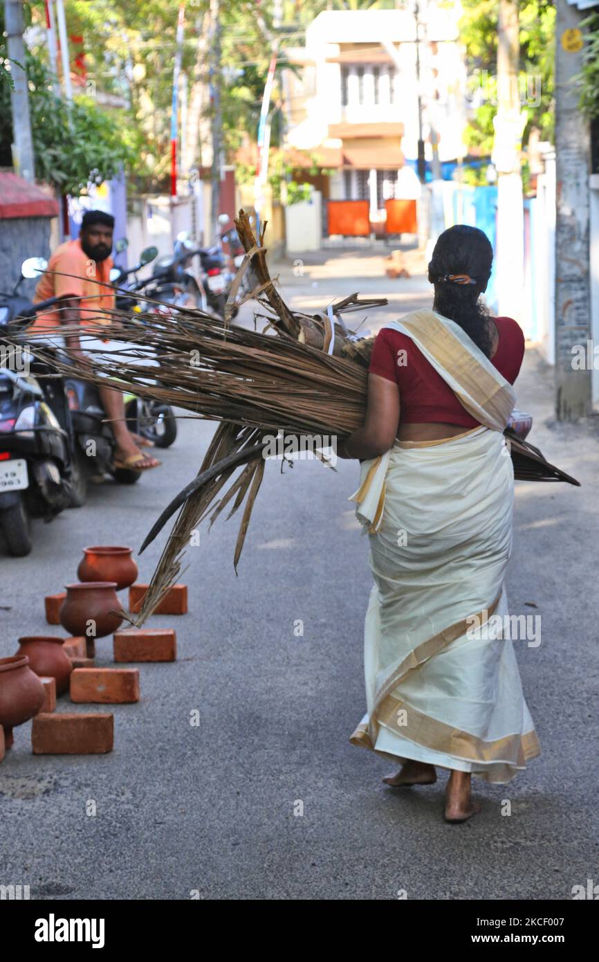 Hindu woman carries a bundle of dried coconut flower sheaths (kothumbu ...