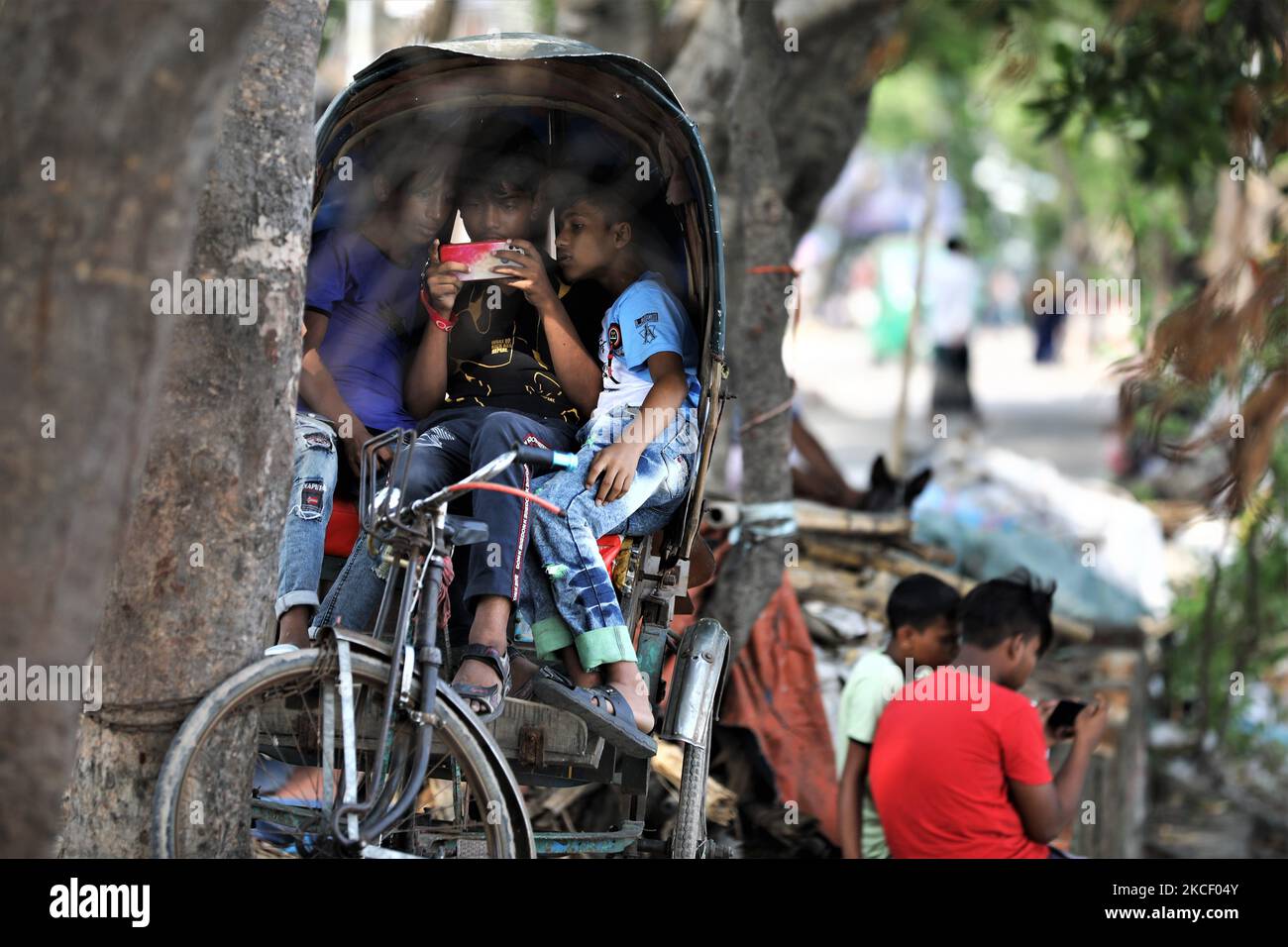 Children play games on smartphones as they sit in a Rickshaw in Dhaka ...