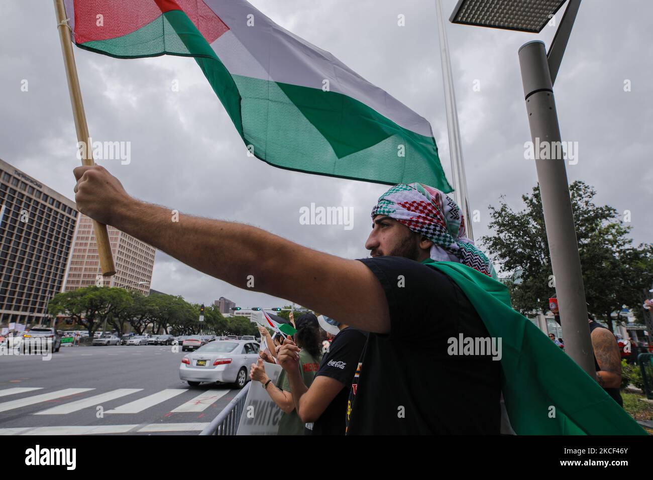 A protestor somberly and proudly holds the flag of Palestine as passing ...