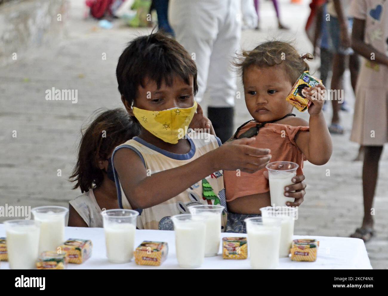 A poor child takes a glass of milk and a packet of biscuits during a ...