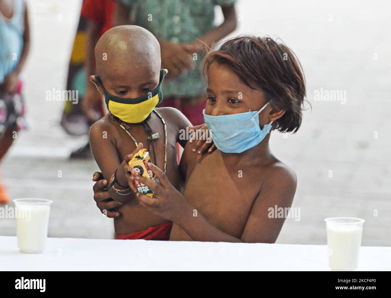 A poor child takes a glass of milk and a packet of biscuits during a ...