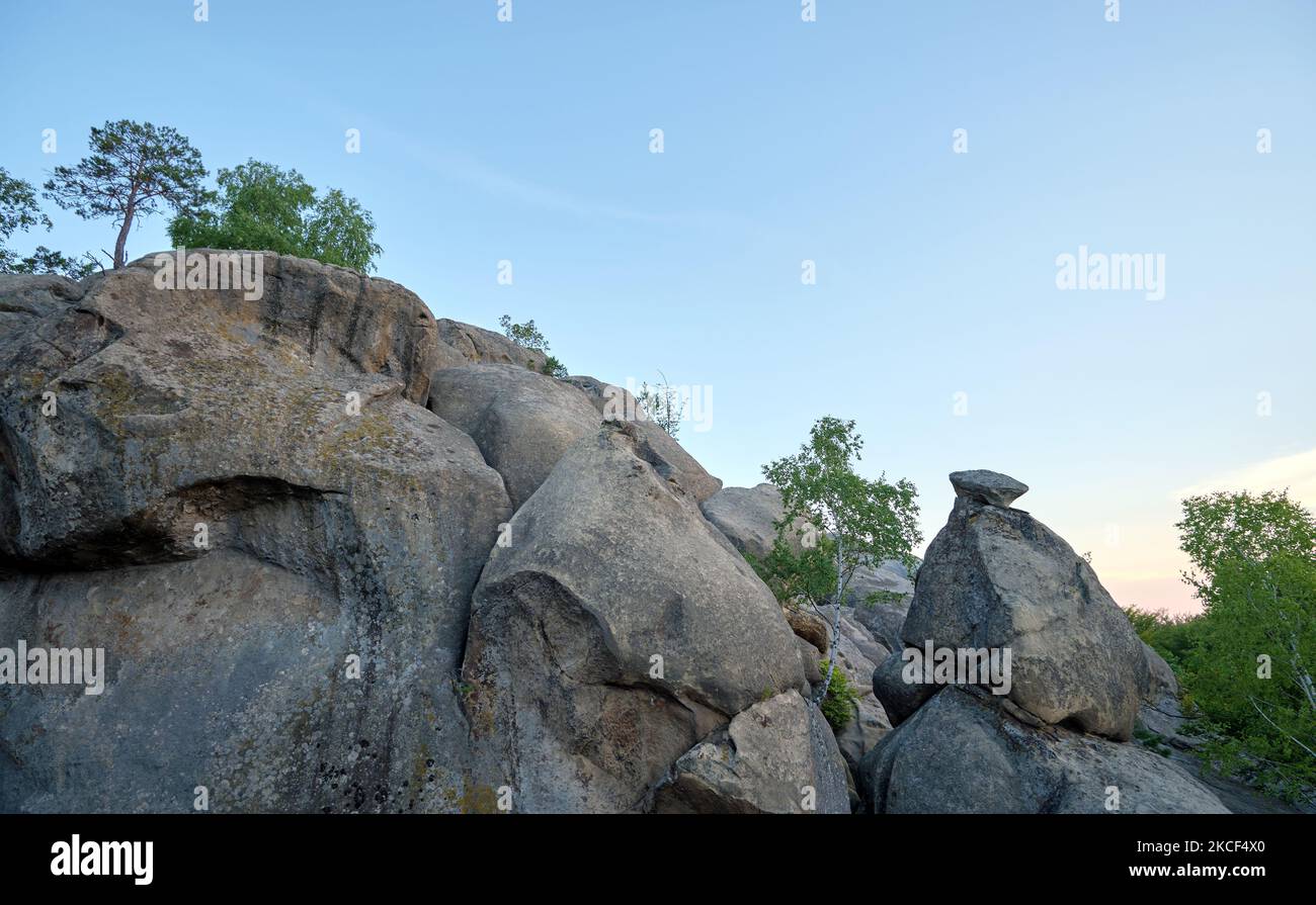 Huge rocky boulder formations high in mountains with growing trees on ...