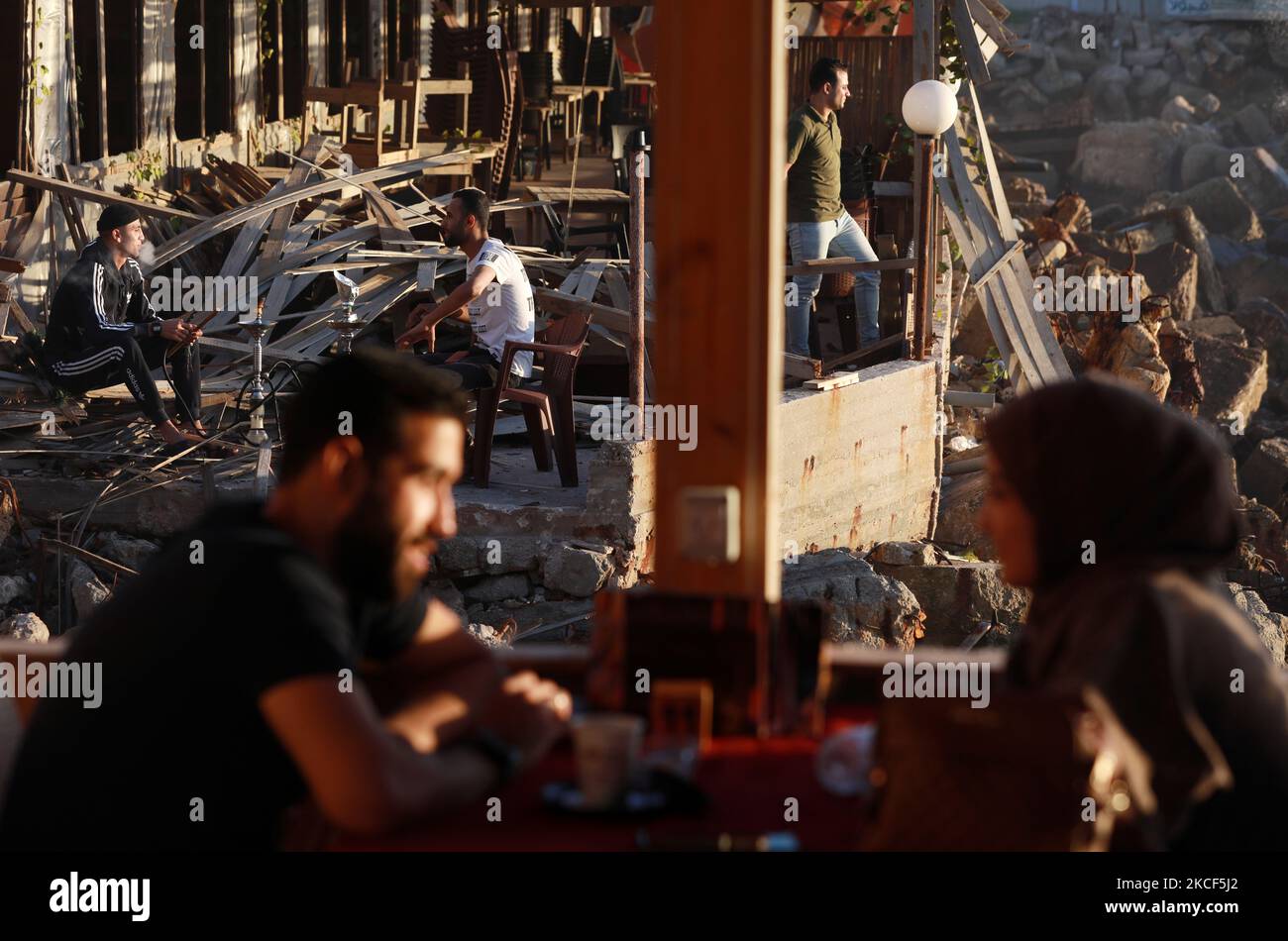 Palestinians smoke a water pipe at the side of Israeli airstrike in ...