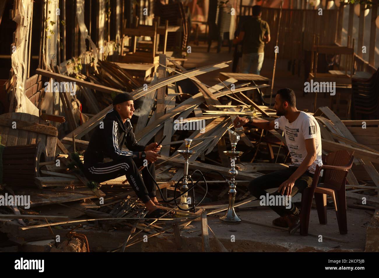 Palestinians smoke a water pipe at the side of Israeli airstrike in ...