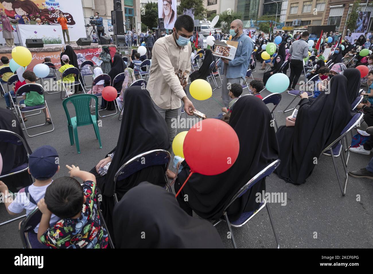 An Iranian man distributes sweets for people and children who attended ...