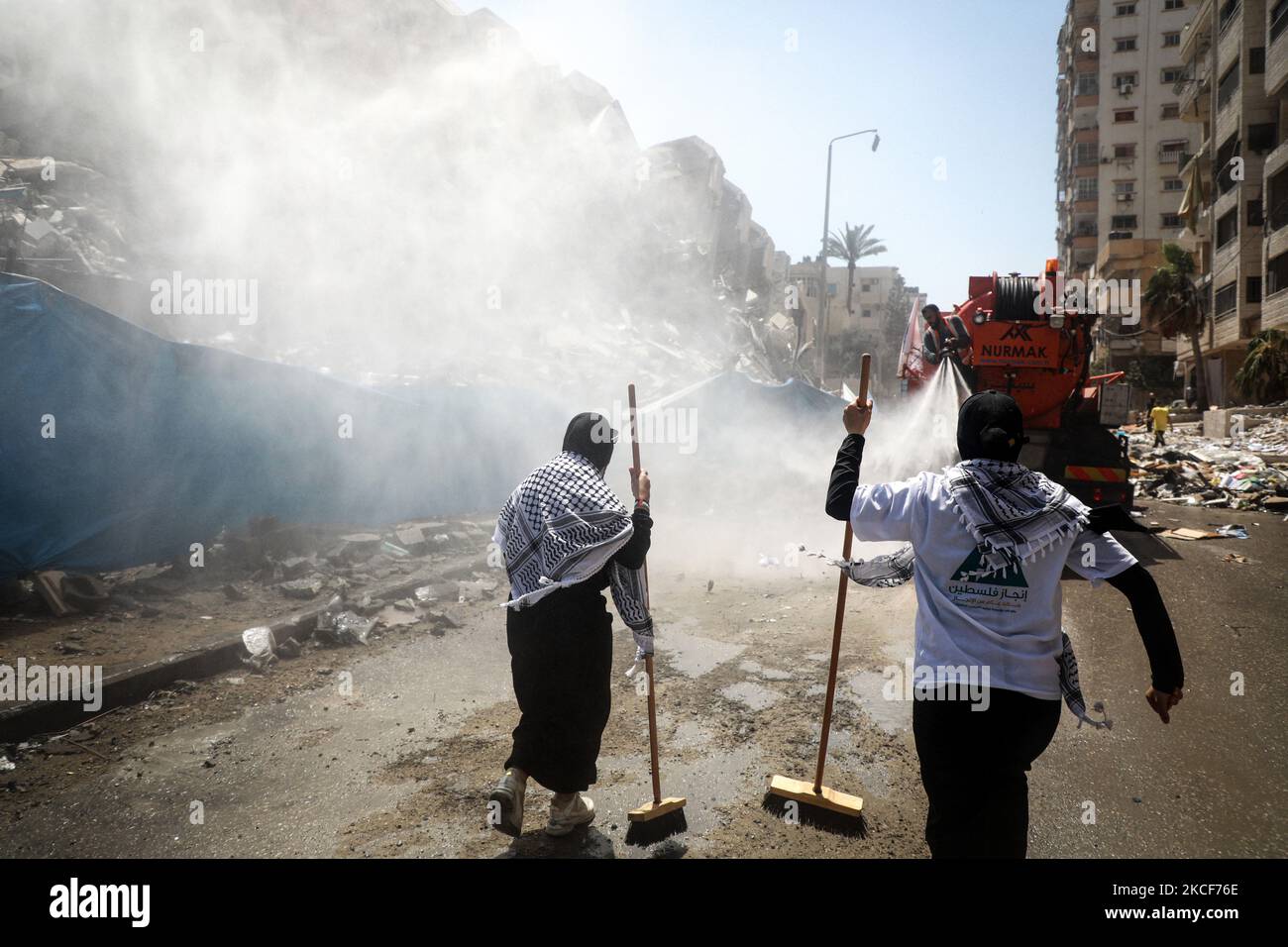 Palestinian volunteers sweep the rubble of buildings, recently ...