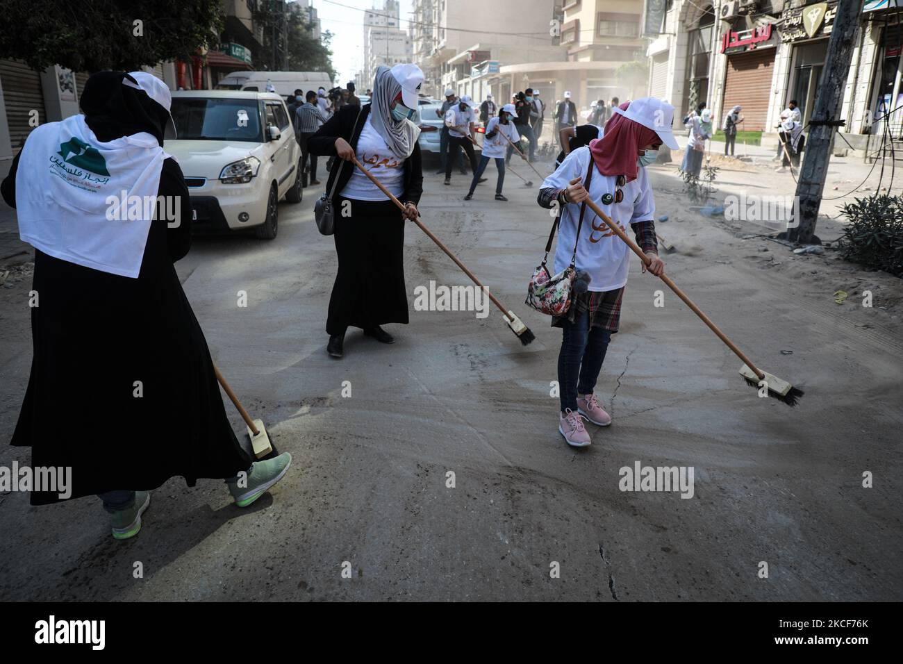 Palestinian volunteers sweep the rubble of buildings, recently ...