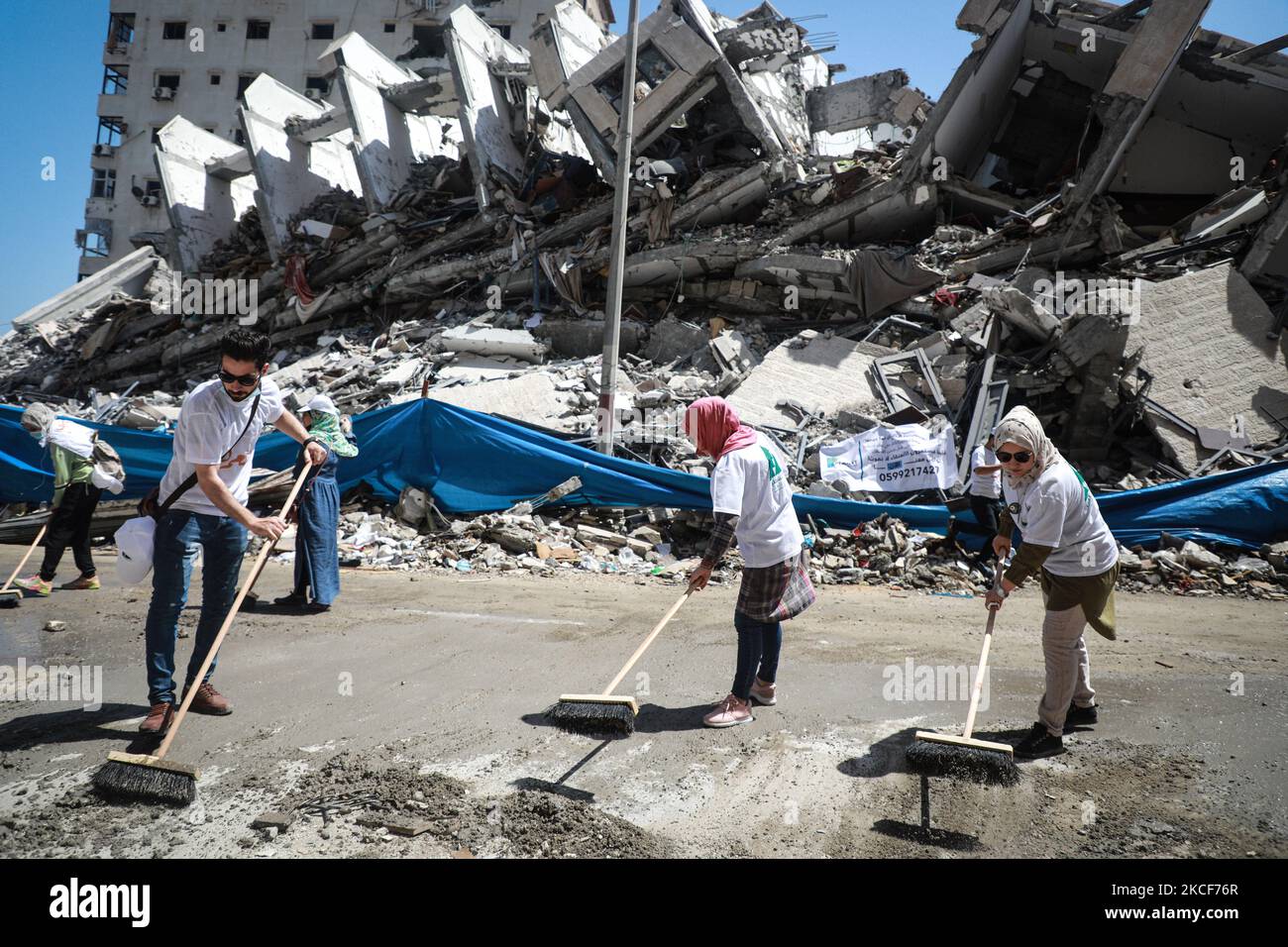 Palestinian volunteers sweep the rubble of buildings, recently ...
