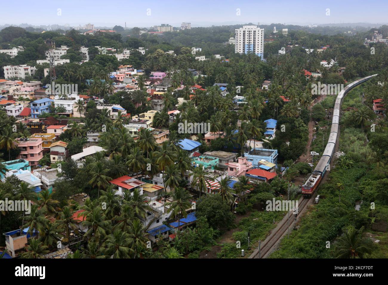 Passenger train travels past houses in the city of Thiruvananthapuram ...