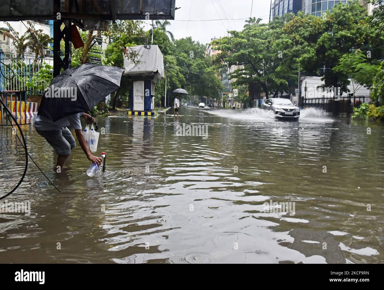 A man fills up drinking water in a bottle on a flooded street after a ...