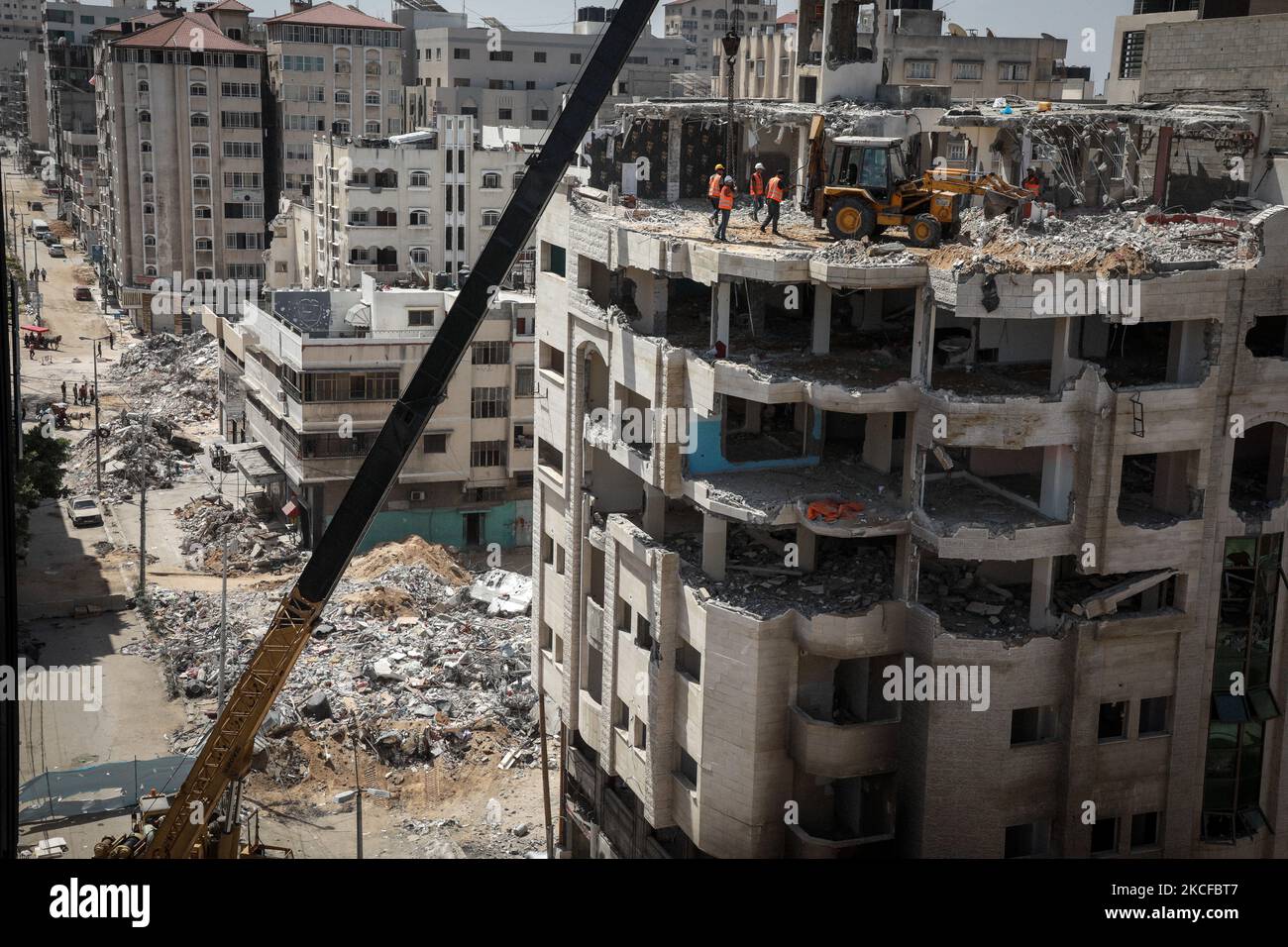 Palestinian workers demolish a building that was damaged during last ...
