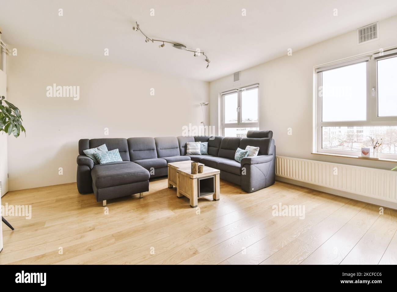 Simple interior of light living room with gray sofa in front of TV and ...