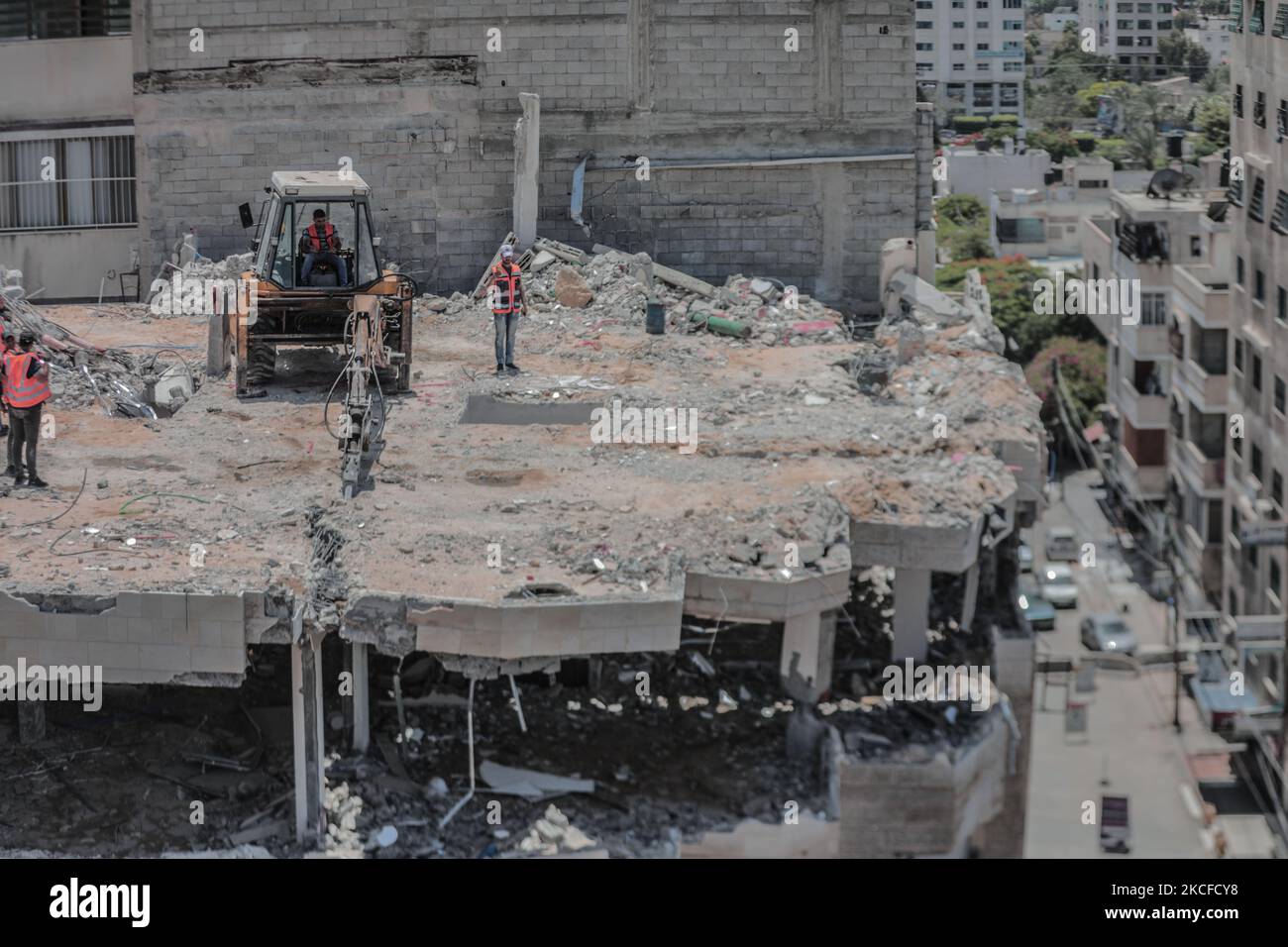 Heavy construction equipment is used to demolish a building destroyed ...