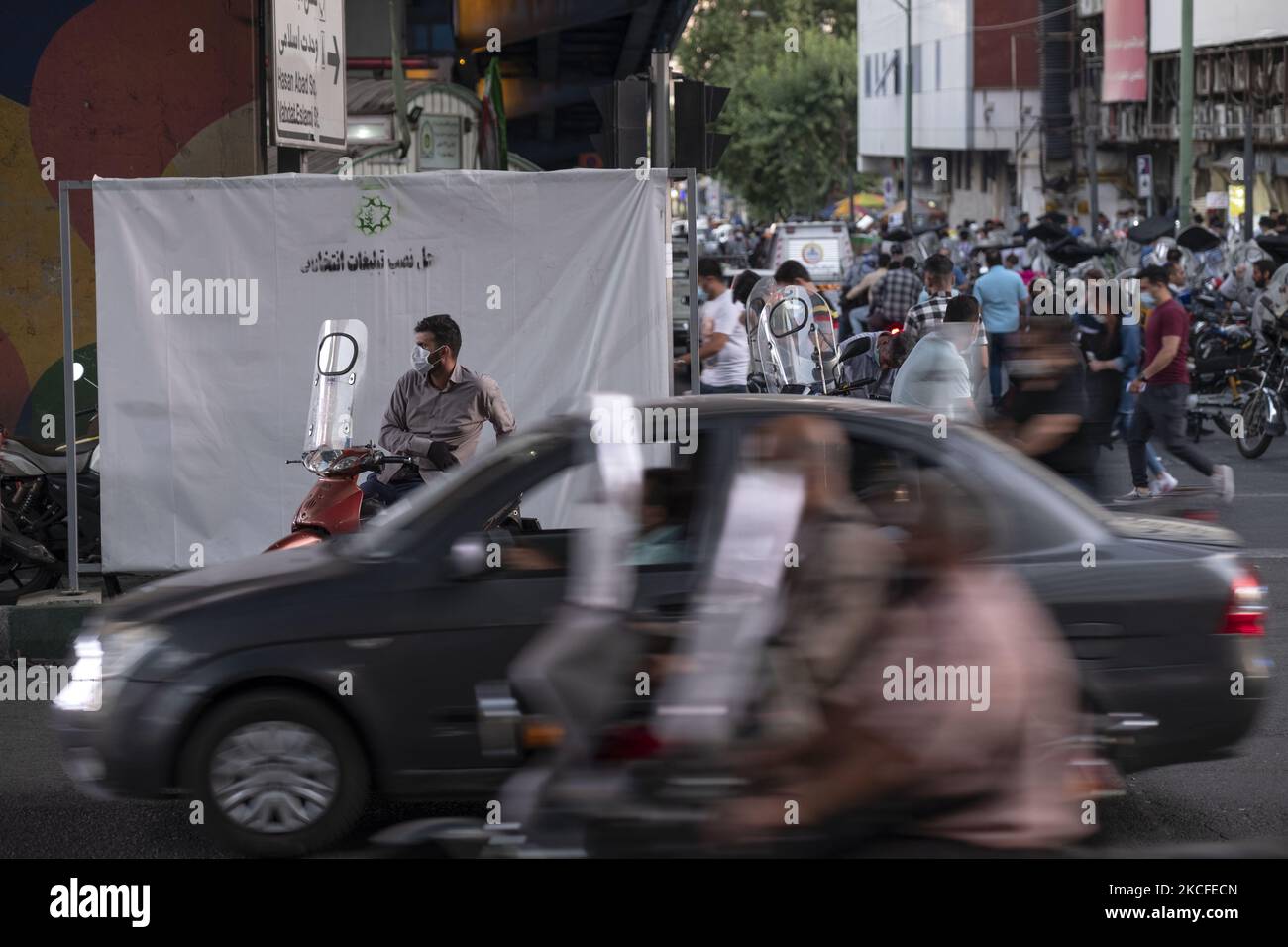 An Iranian motor taxi driver sits on his motorcycle in front of a ...