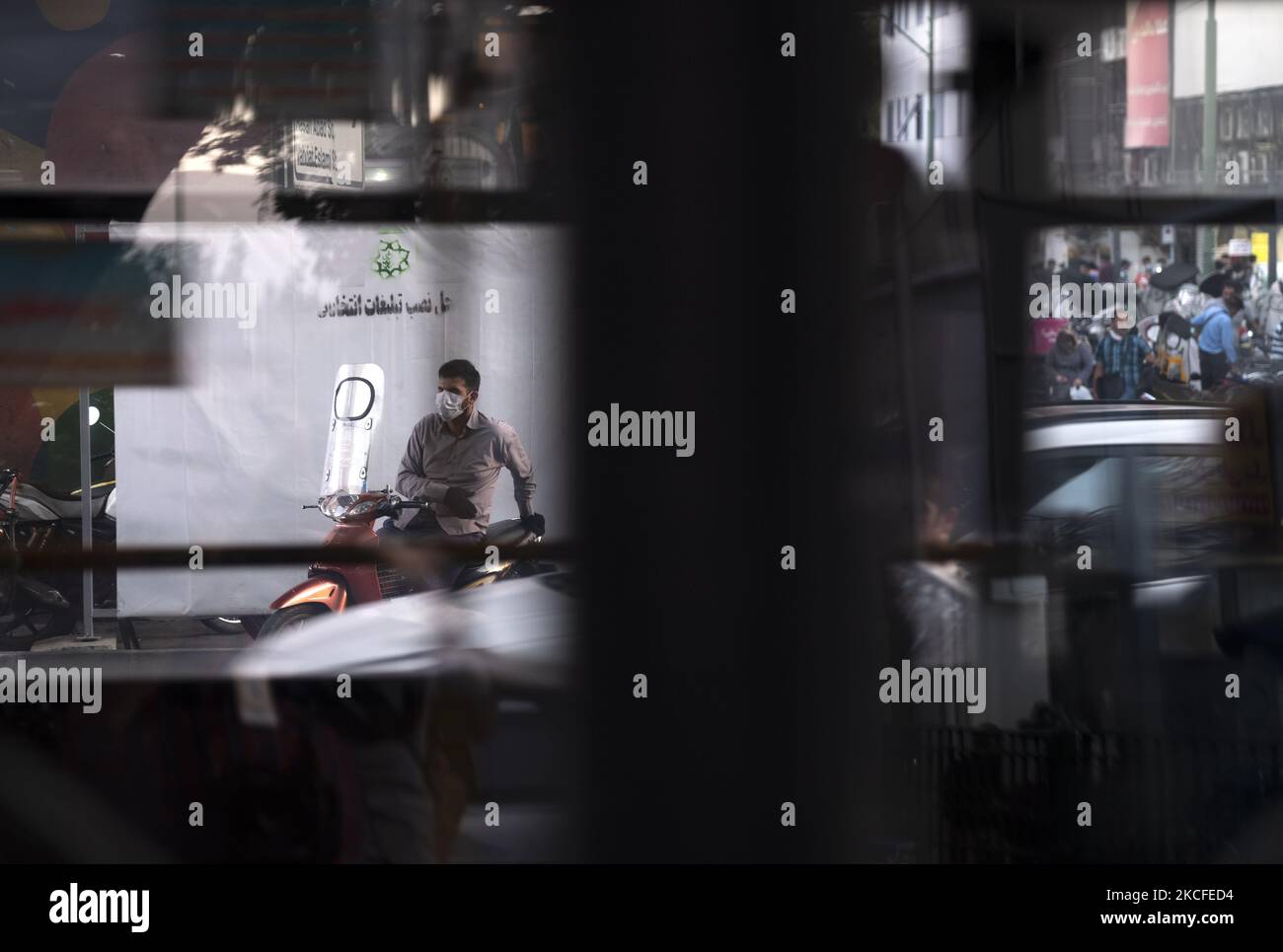 An Iranian motor taxi driver sits on his motorcycle in front of a ...