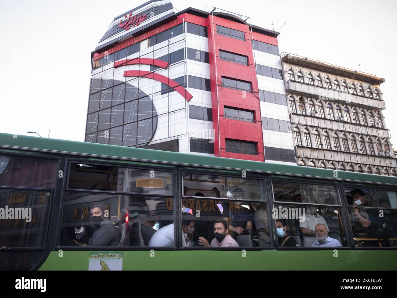 Iranian men look on as they sit on a bus that is stopped at a crossroad ...