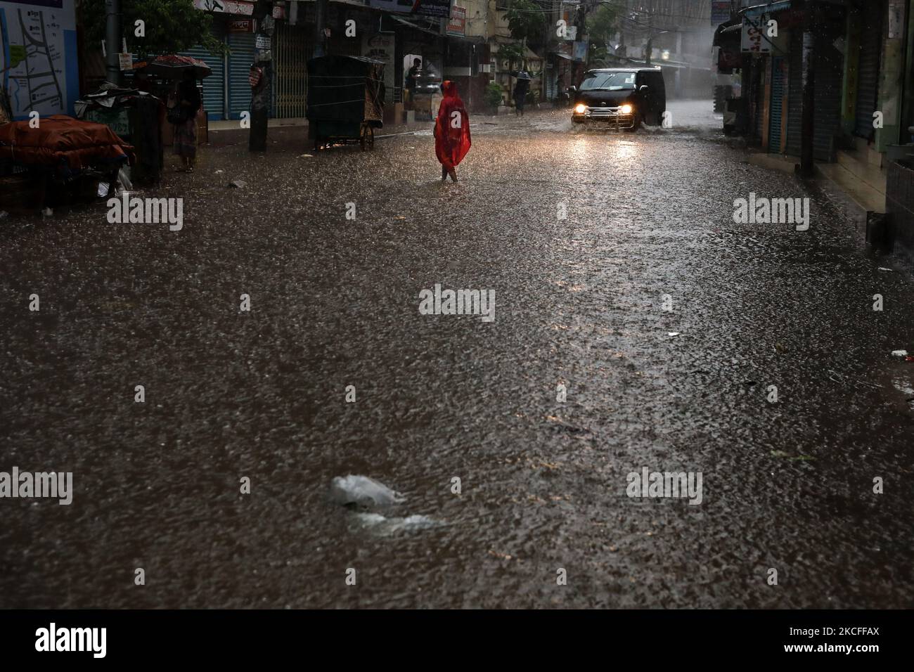 A woman walks on the street in the rain at morning in Dhaka, Bangladesh ...