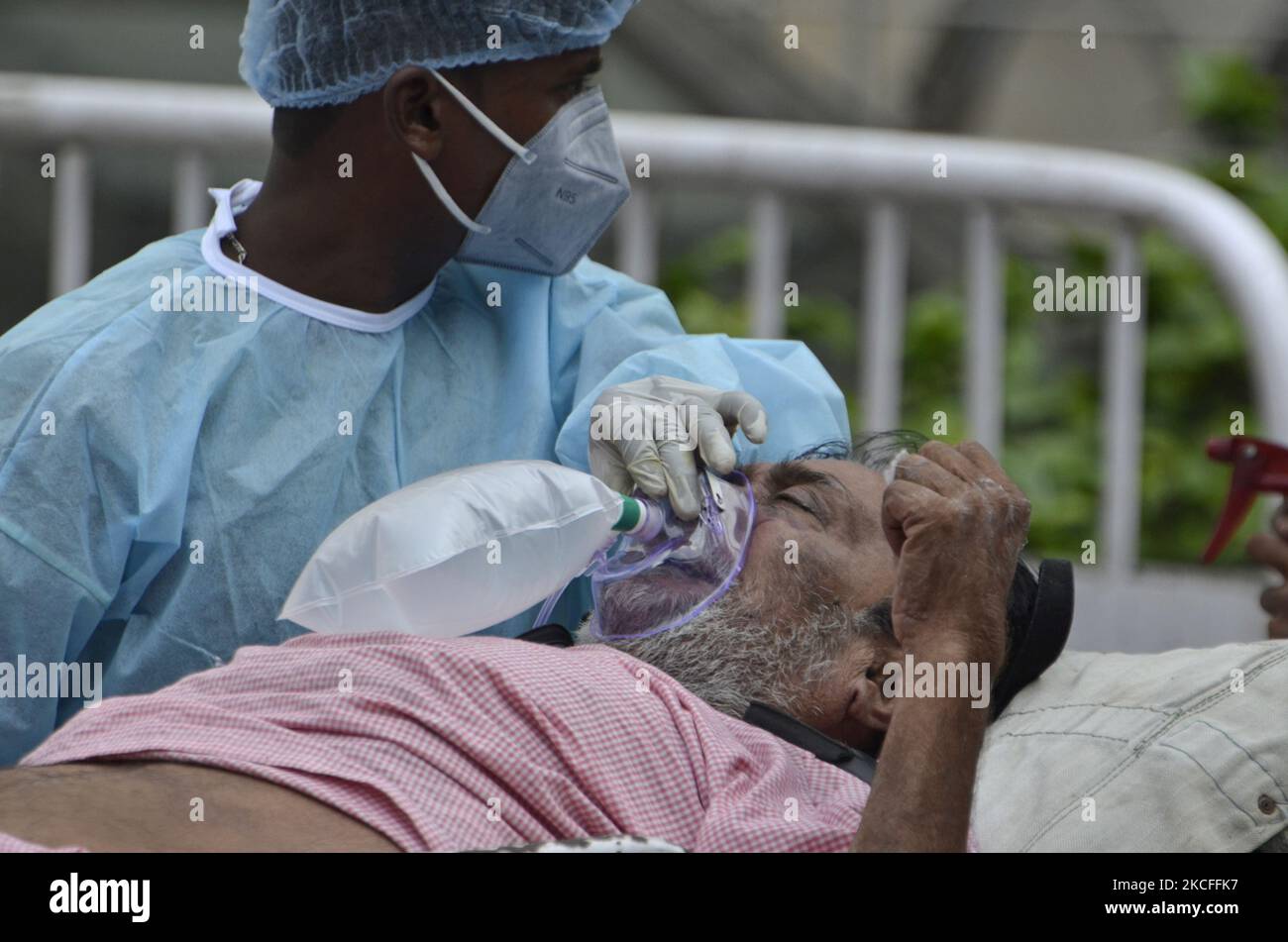 A health worker helps to put an oxygen mask on Covid-19 patient's face ...
