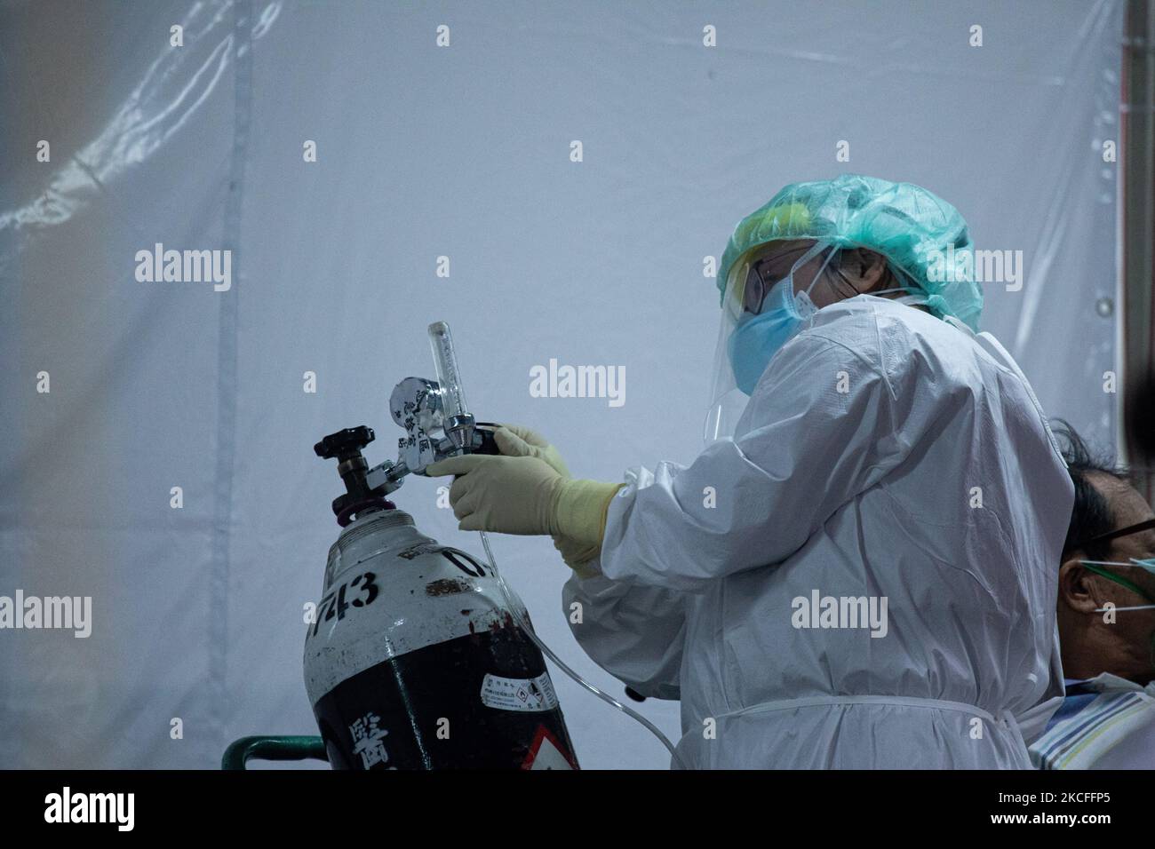 A medical worker wearing protective suits seen adjusting an oxygen ...