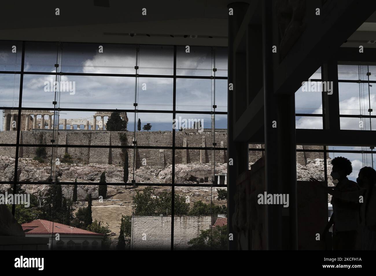 Tourists walk at the new Acropolis museum with the ancient temple of ...