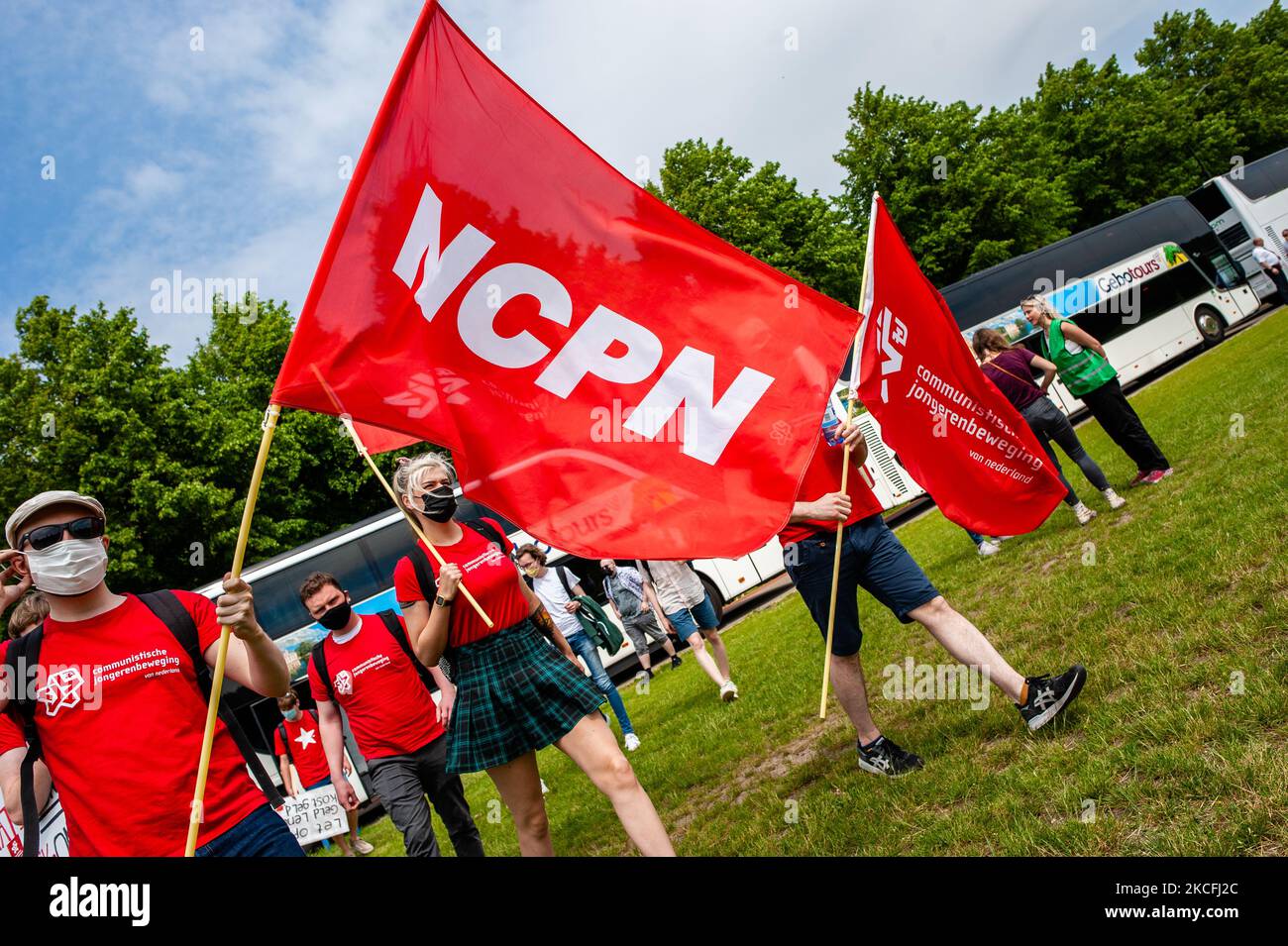 A group of students holding big flags are arriving by bus to the ...