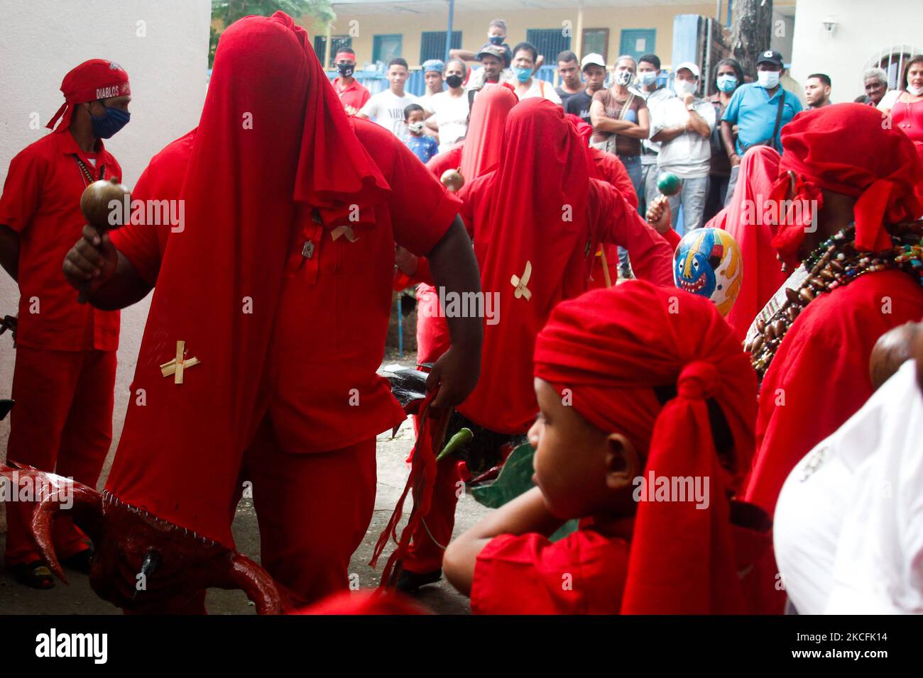 Men dressed as Diablos dance and play maracas in front of an altar ...