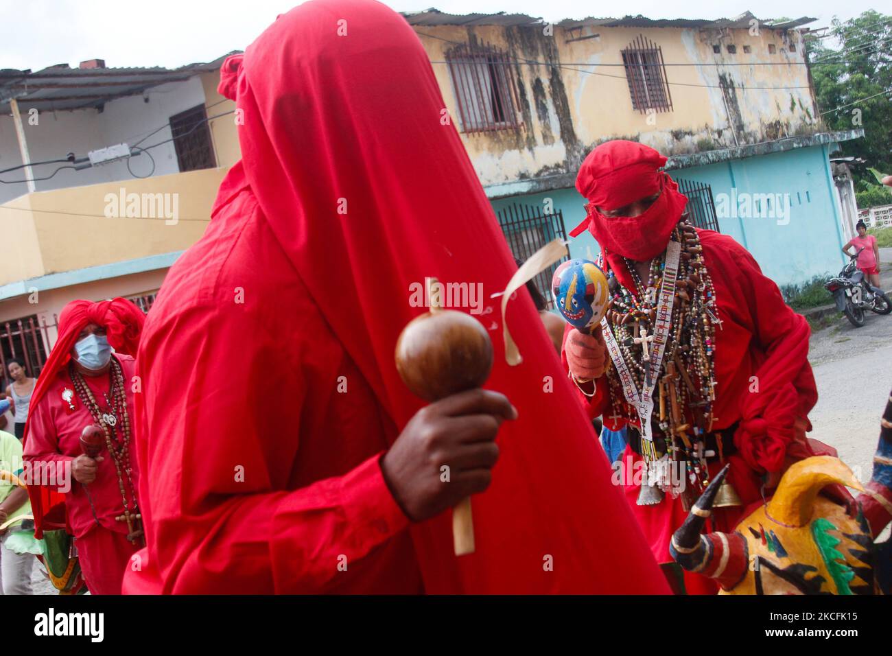 Men dressed as Diablos dance and play maracas in front of an altar ...