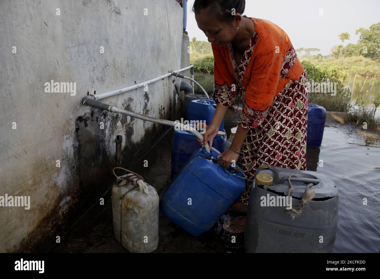 Villagers queuing for clean water from the mosque water tank, which is ...