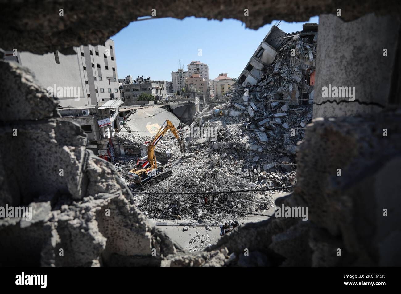 An excavator run by an Egyptian team clears up the rubble of Al-Shorouk ...