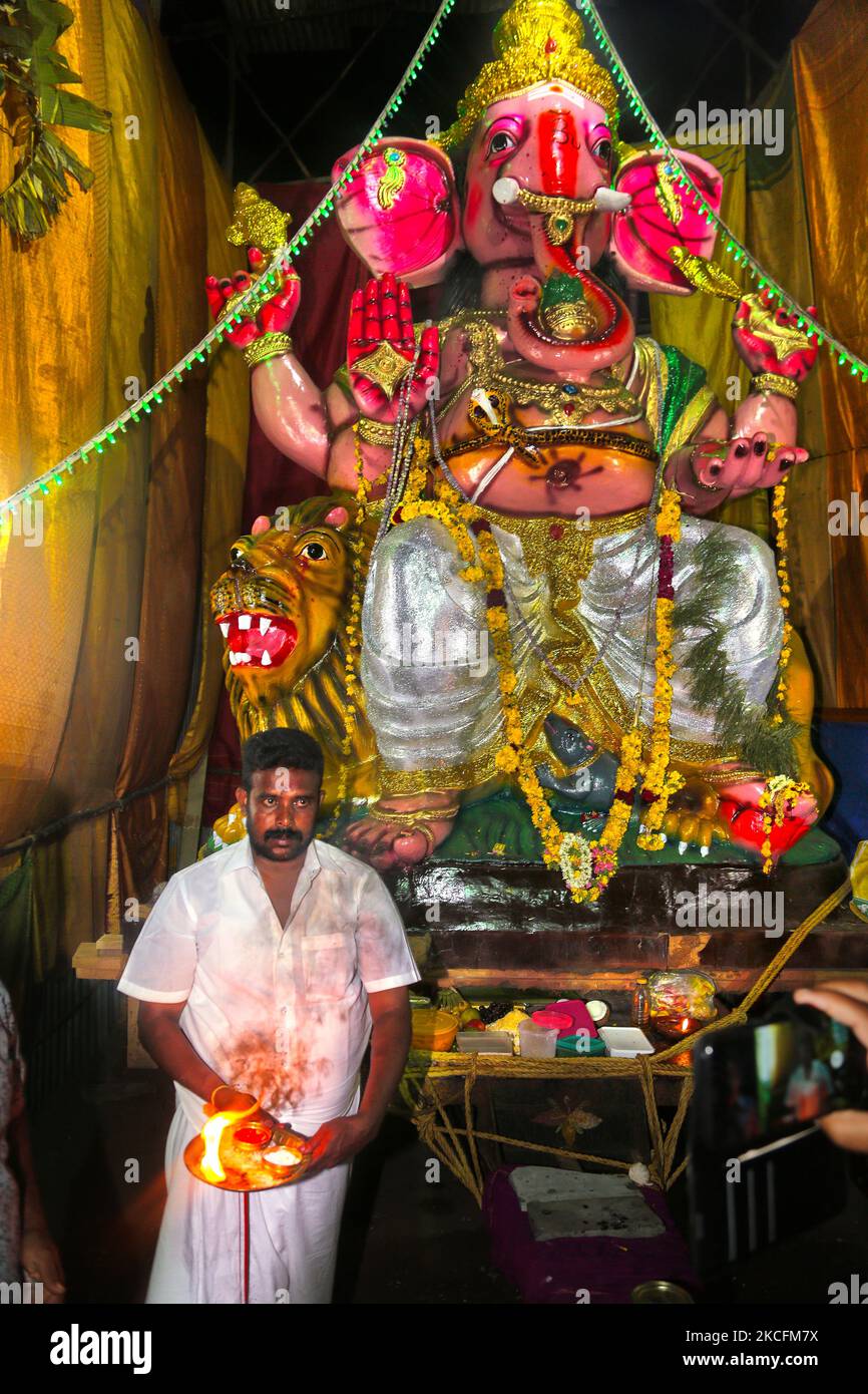 Tamil Hindu priest performs prayers by a large clay idol of Lord Ganesha (Lord Ganesh) at a ...