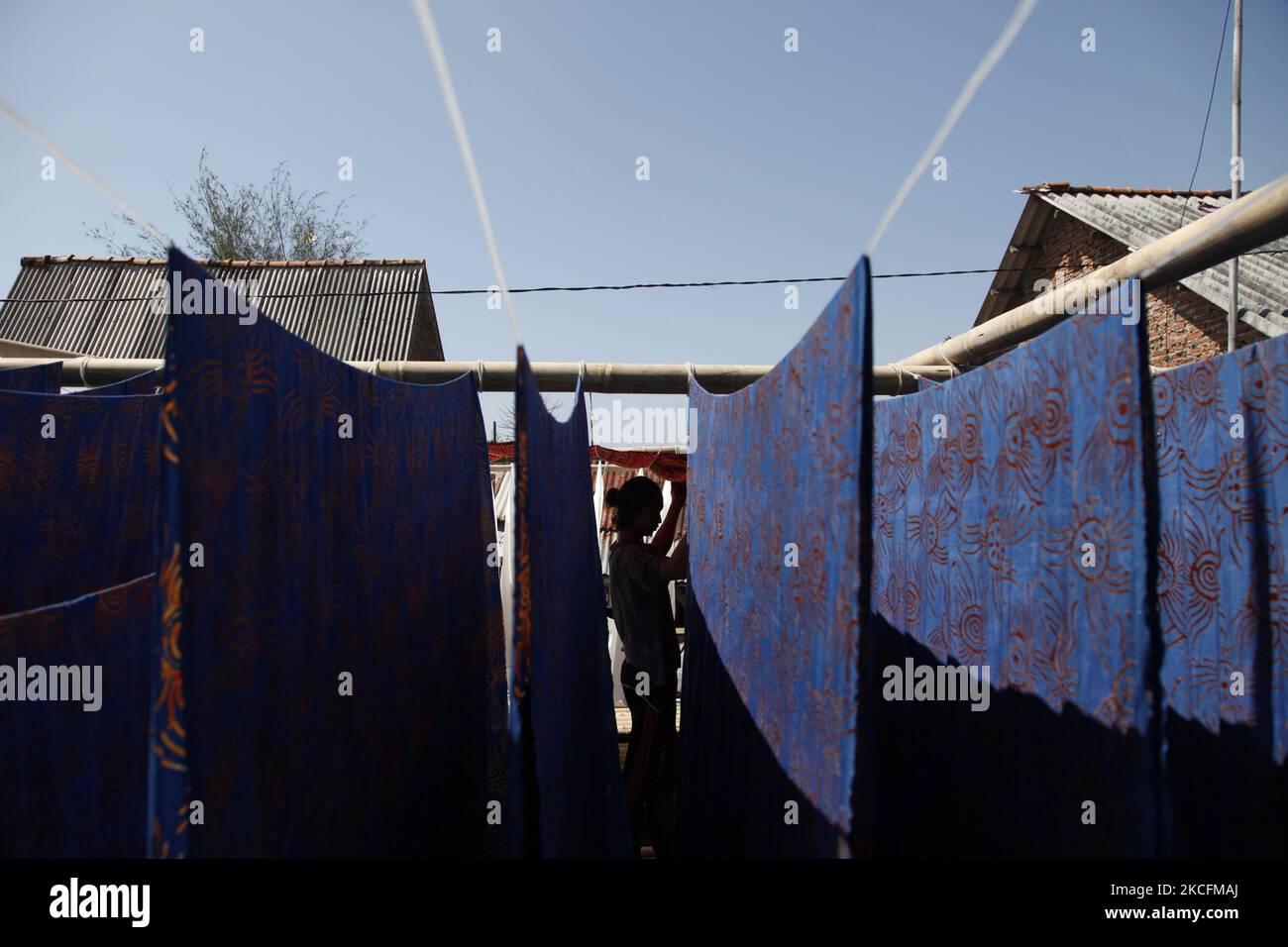 Worker drying the batik cloths after going through the coloring and ...
