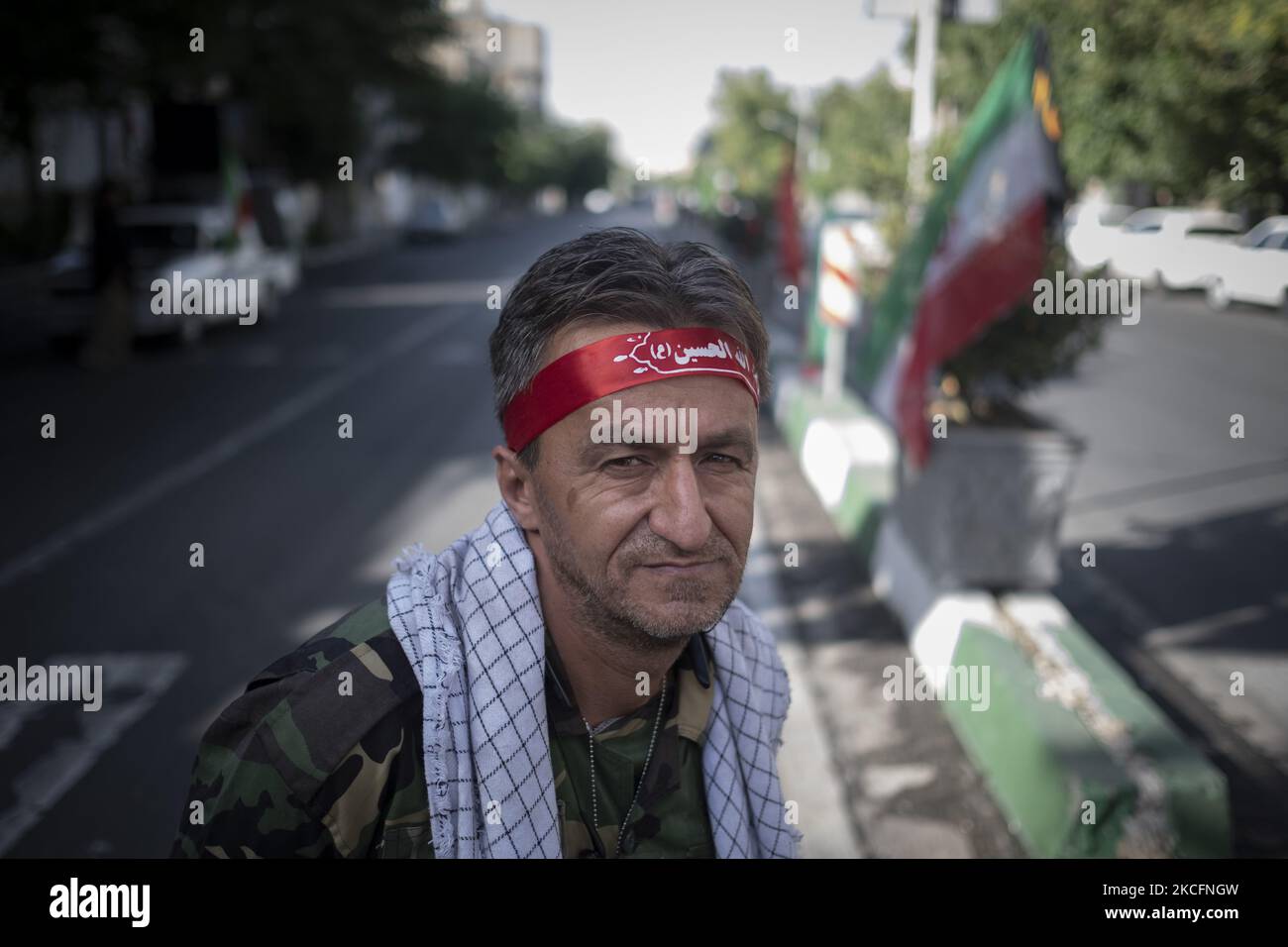 An Iranian man wearing a military uniform and a headband looks on while ...
