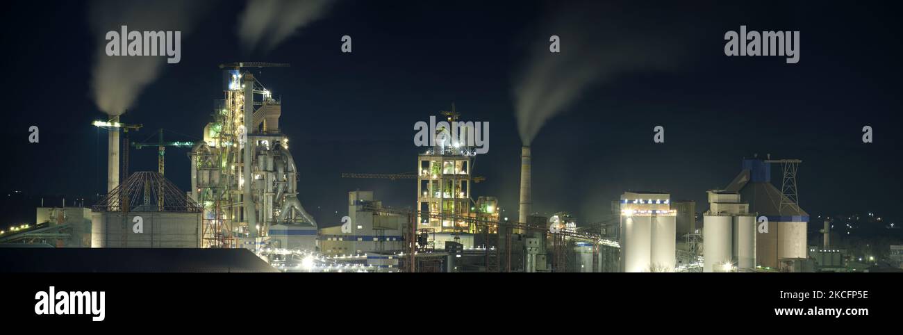 Illuminated cement plant with high factory structure and tower cranes ...