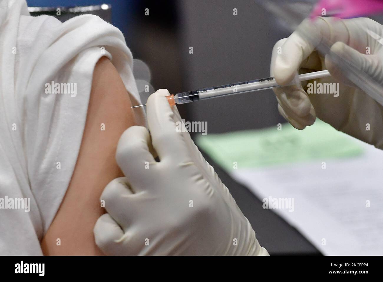 A health worker administers the AstraZeneca COVID-19 vaccine to people at vaccination site ...