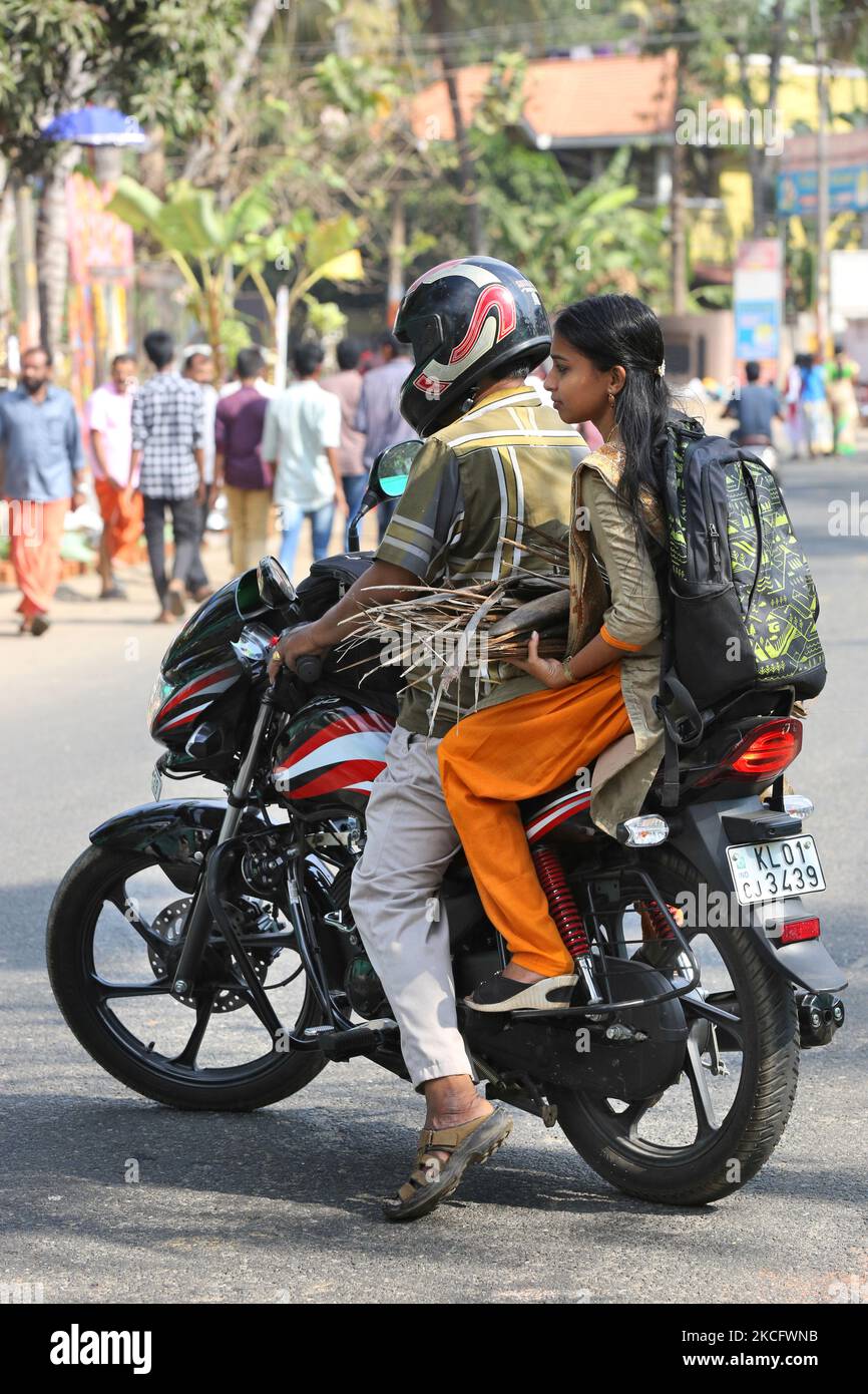 Woman on a bike carries a bundle of dried coconut flower sheaths ...