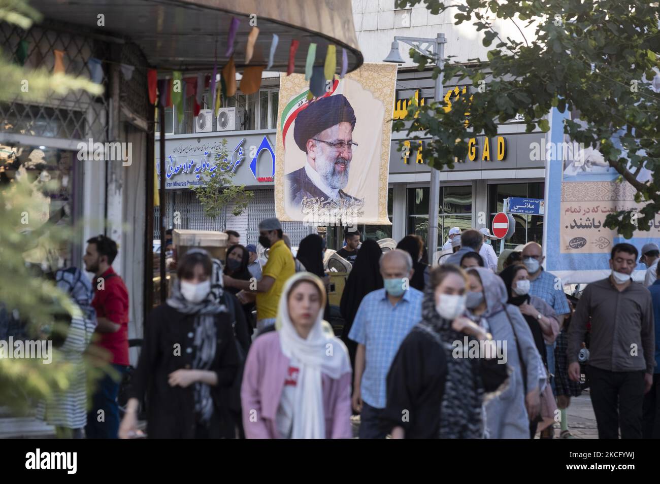 Iranian people walk under an electoral billboard for presidential ...