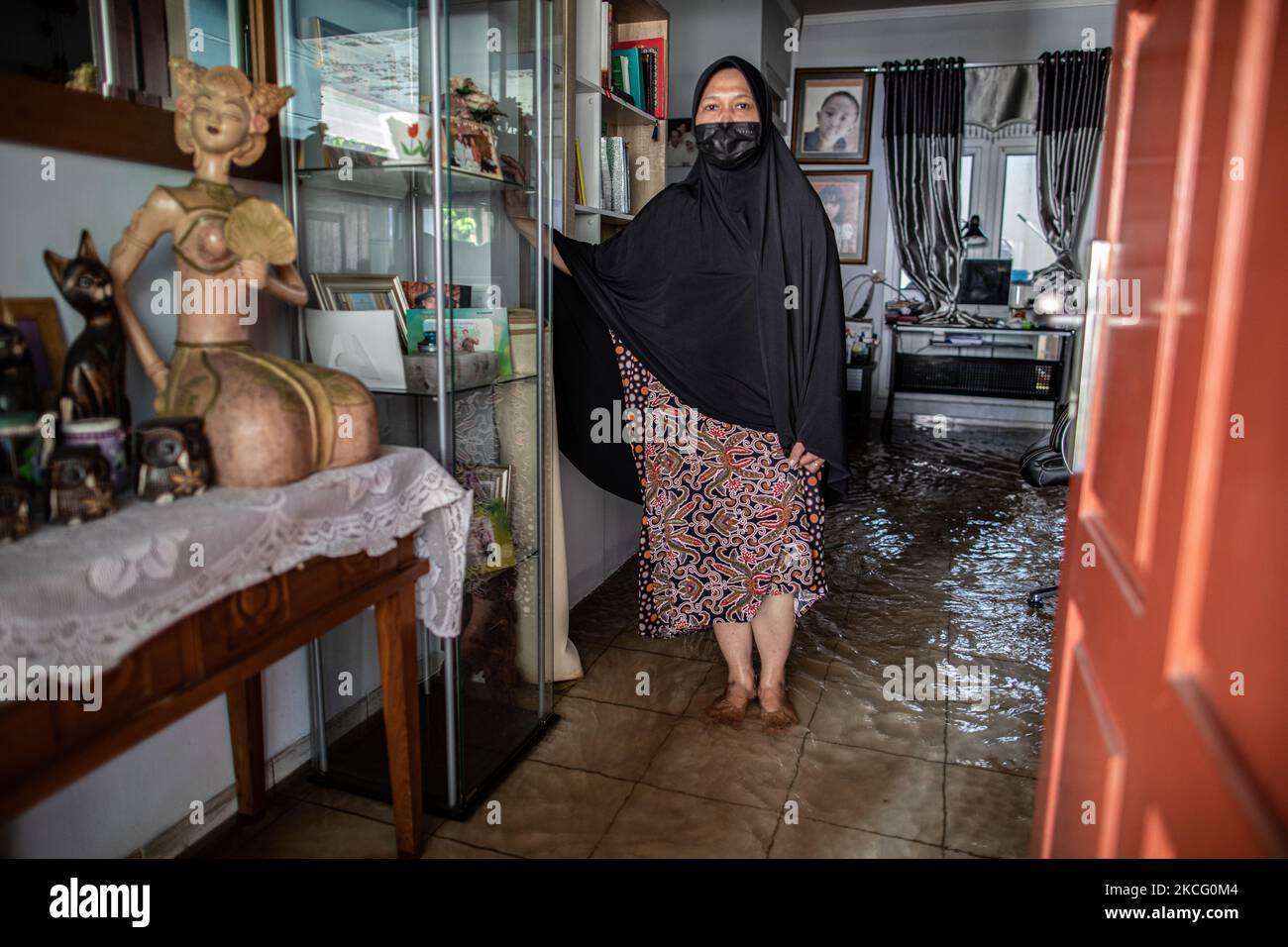 A resident poses at his house which is flooded from the river flow ...