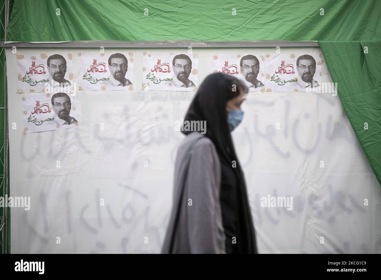 An Iranian woman wearing a protective face mask walks past presidential ...