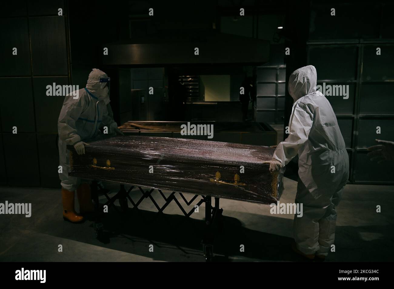 Crematorium workers wearing protective suit push the casket of Covid-19 ...