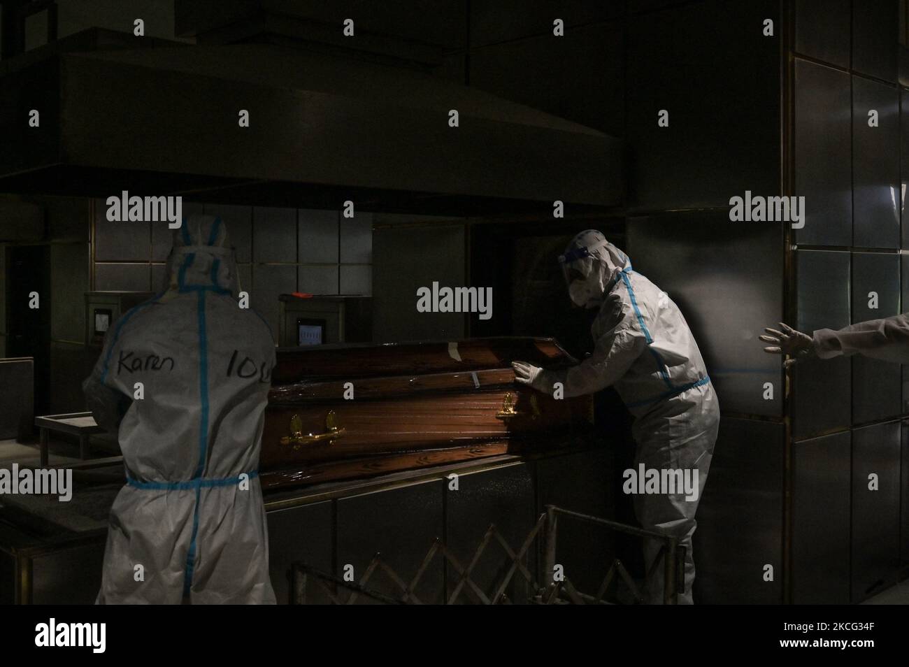 Crematorium workers wearing protective suit push the casket of Covid-19 ...