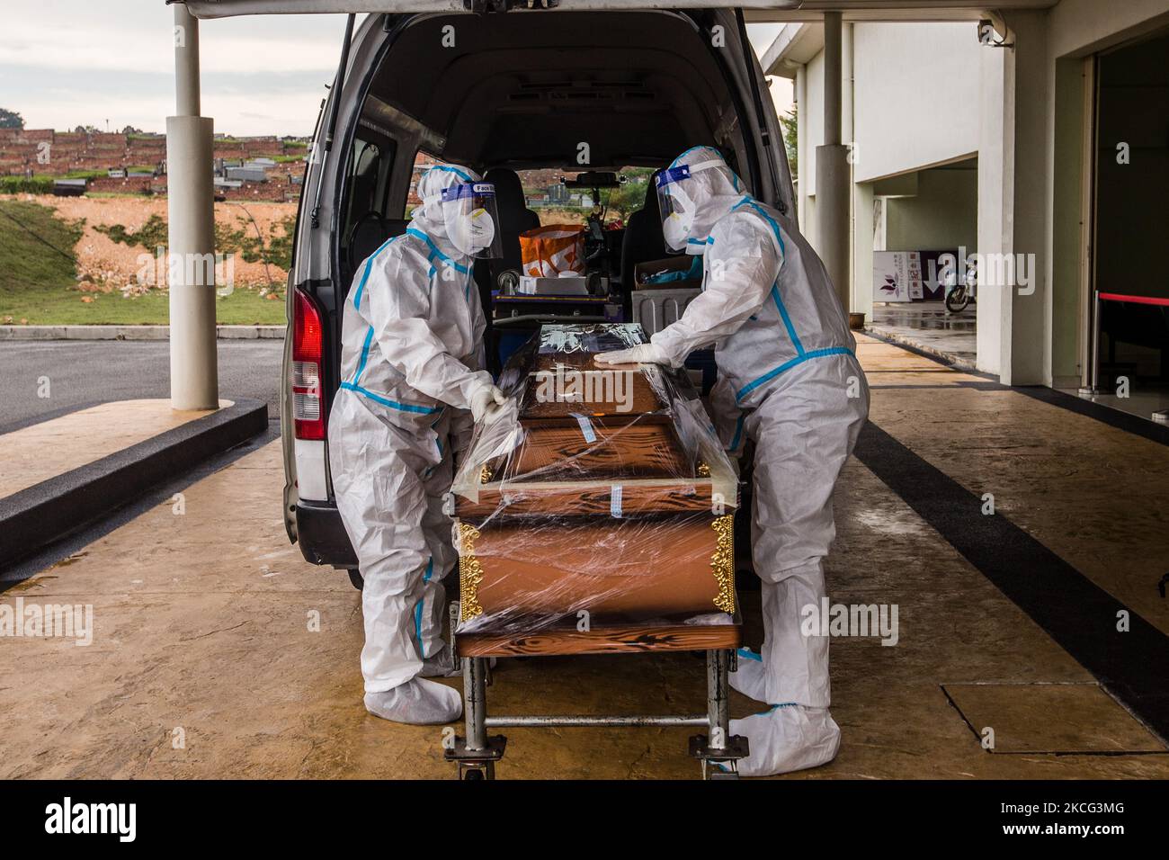 Crematorium workers wearing protective suit carry the casket of Covid ...