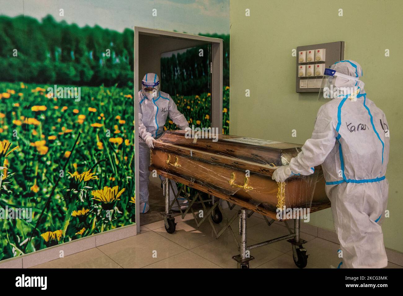 Crematorium workers wearing protective suit push the casket of Covid-19 ...