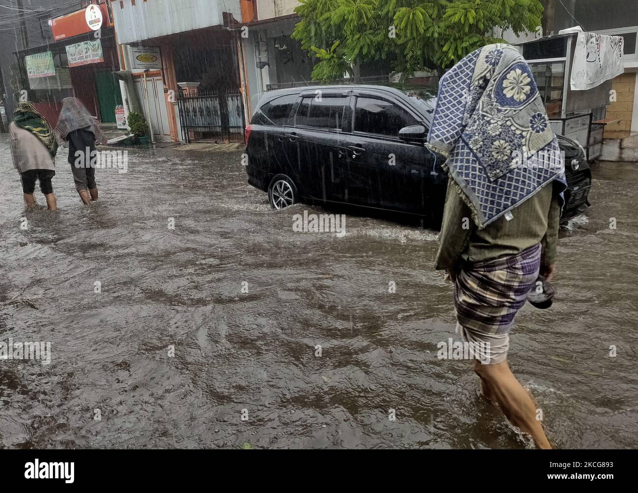 Peoples make their way along a waterlogged street after heavy rains in ...