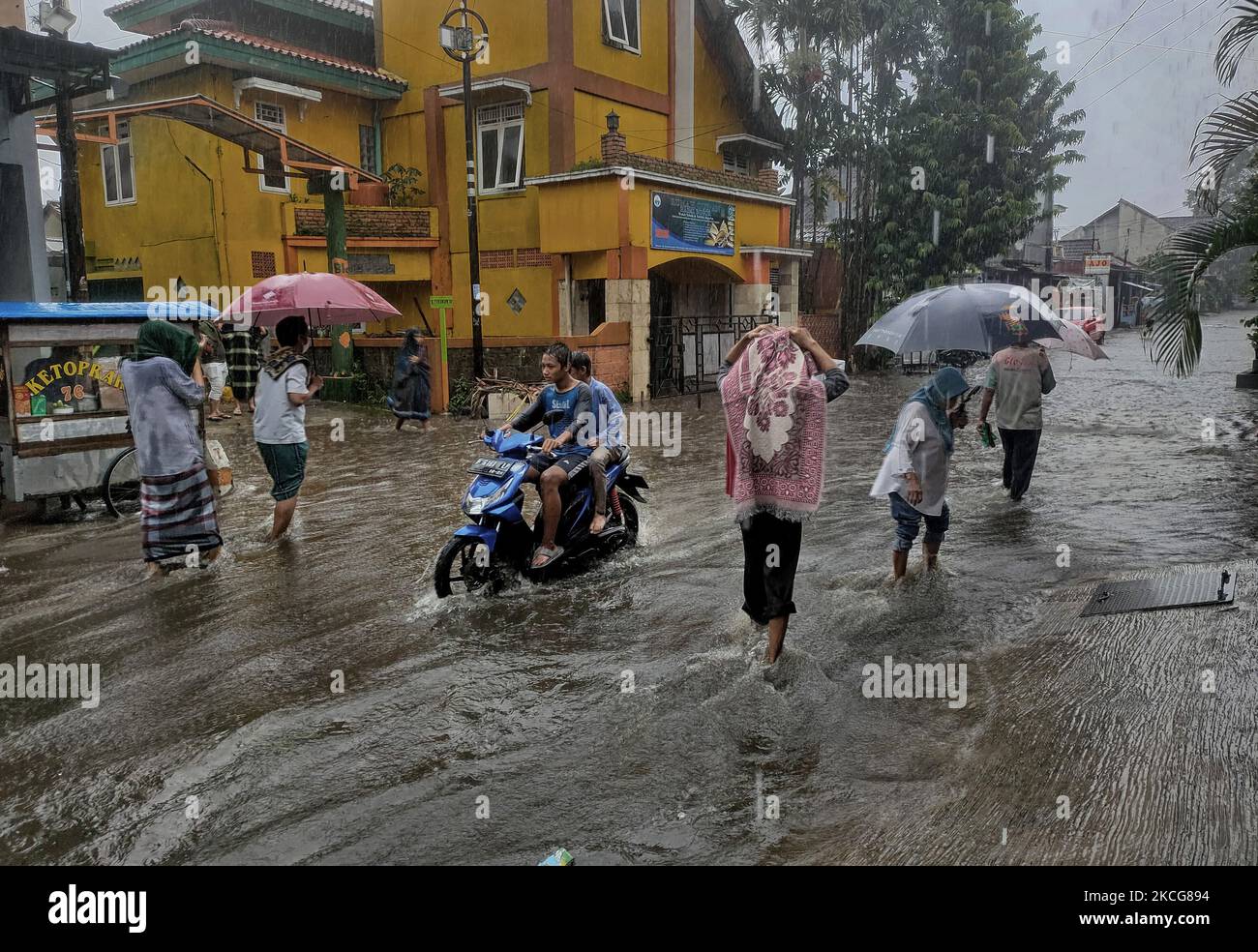 Commuters make their way along a waterlogged street after heavy rains ...